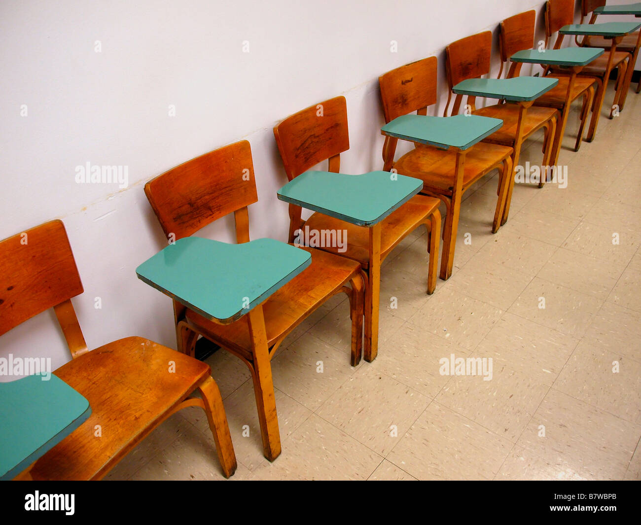 Rows of empty wooden antique desk-chairs with turqouise writing ...