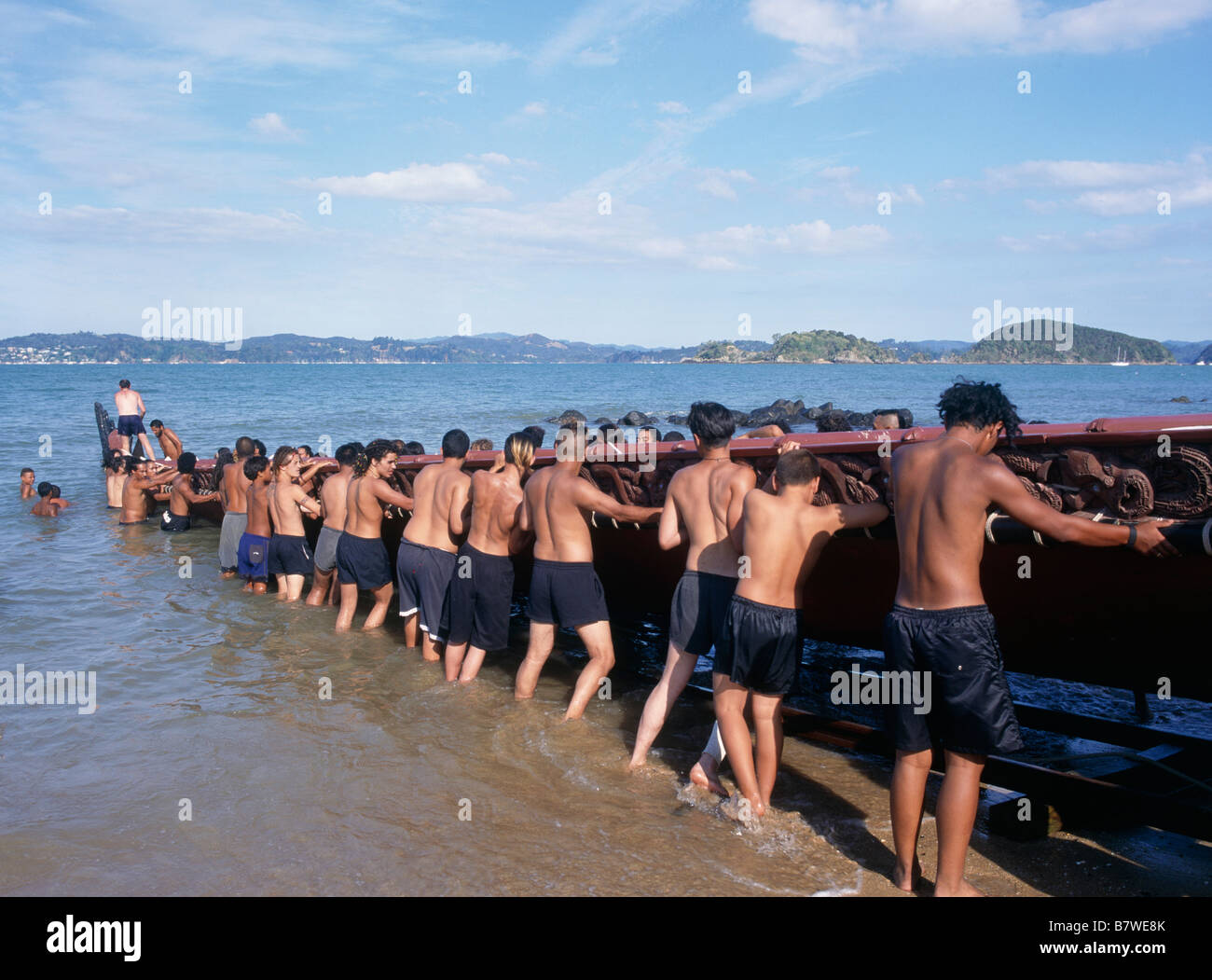 Waitangi Maori warriors launching war canoe Shallow water Bare backs ...