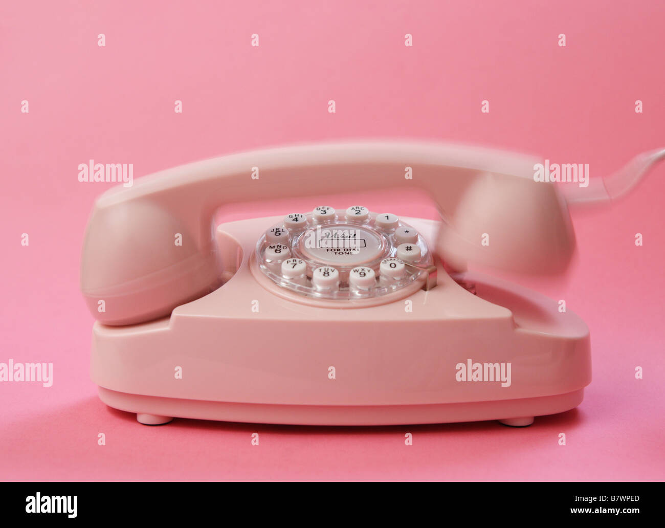 a pink telephone on a pink background appearing to ring and vibrate ...