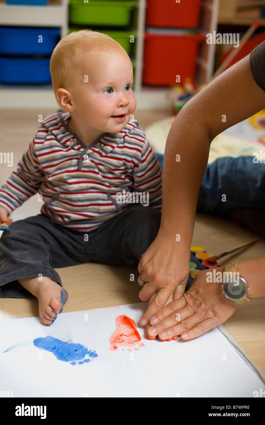Baby girl and mother painting footprints Germany September 2008 Stock ...