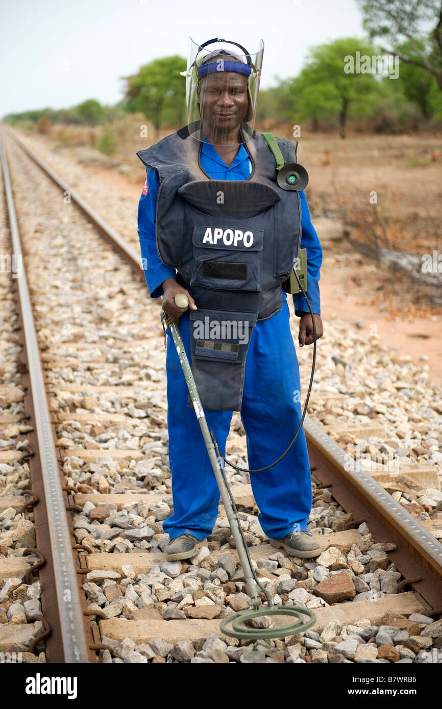 Mozambican deminer with protective gear and metal detector on a railway ...