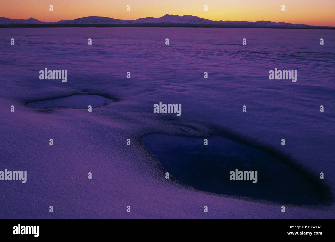 Surface of water covered with snow ice Two melted holes in ice View to ...