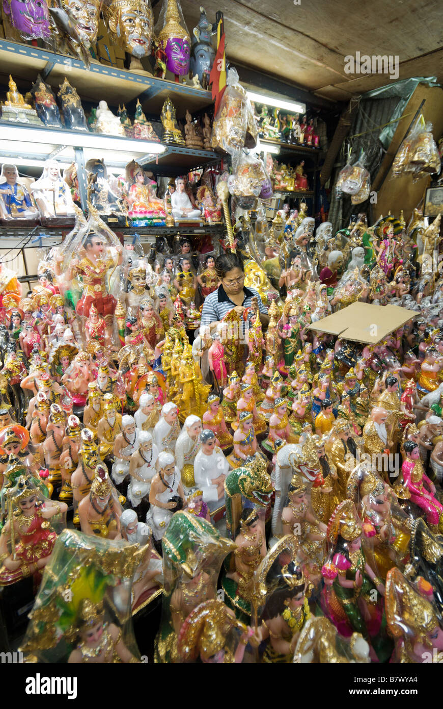 Stall vendor surrounded by plastic Buddhist statuettes and icons for ...