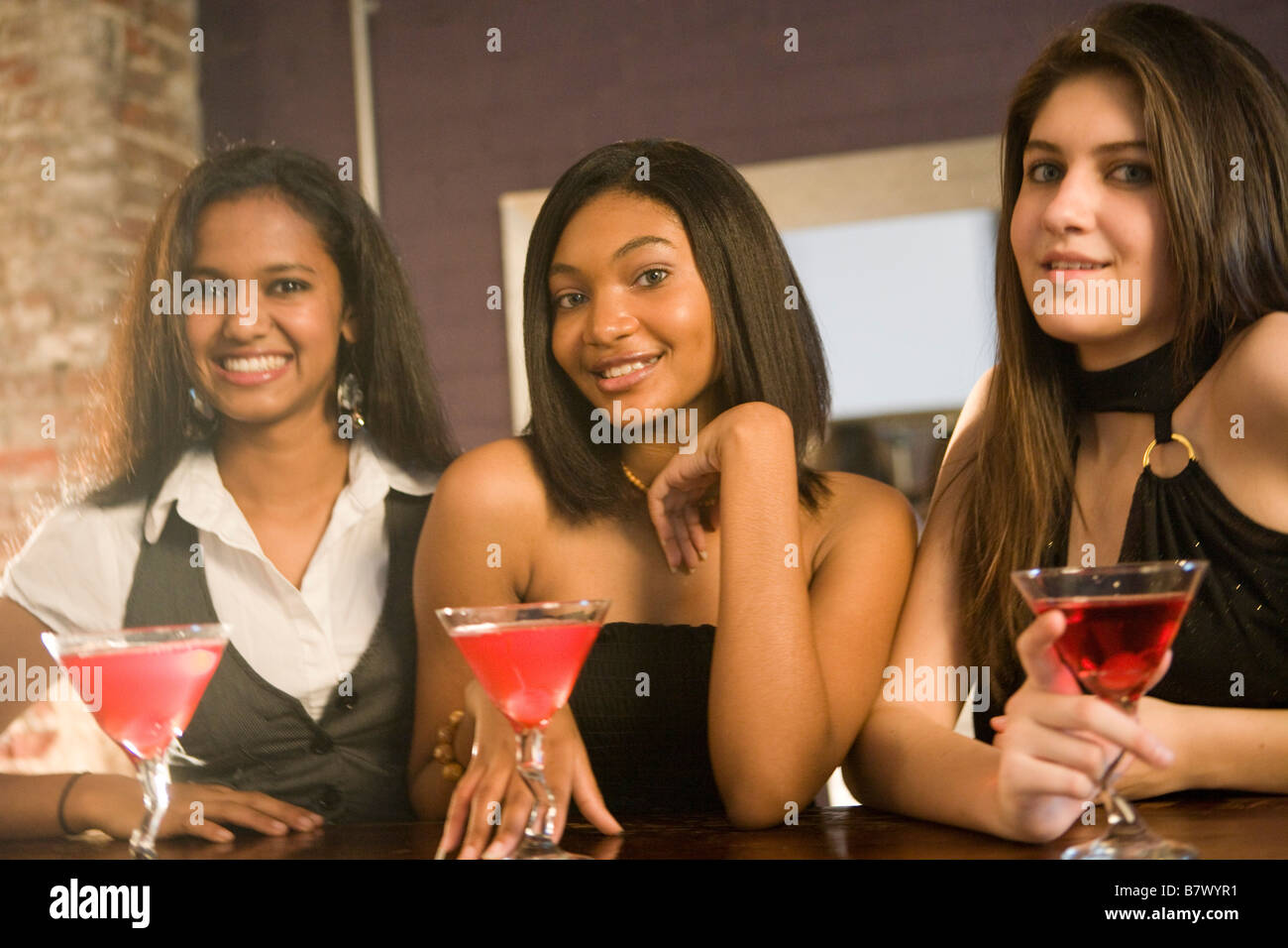 Young women sitting at bar counter drinking cocktails Stock Photo - Alamy
