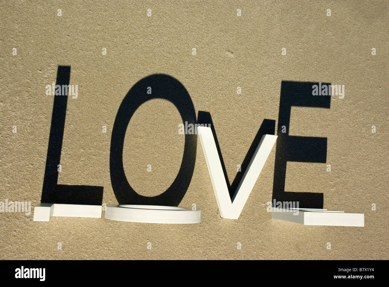 Shadows cast from wooden block letters to create the word "love" on ...