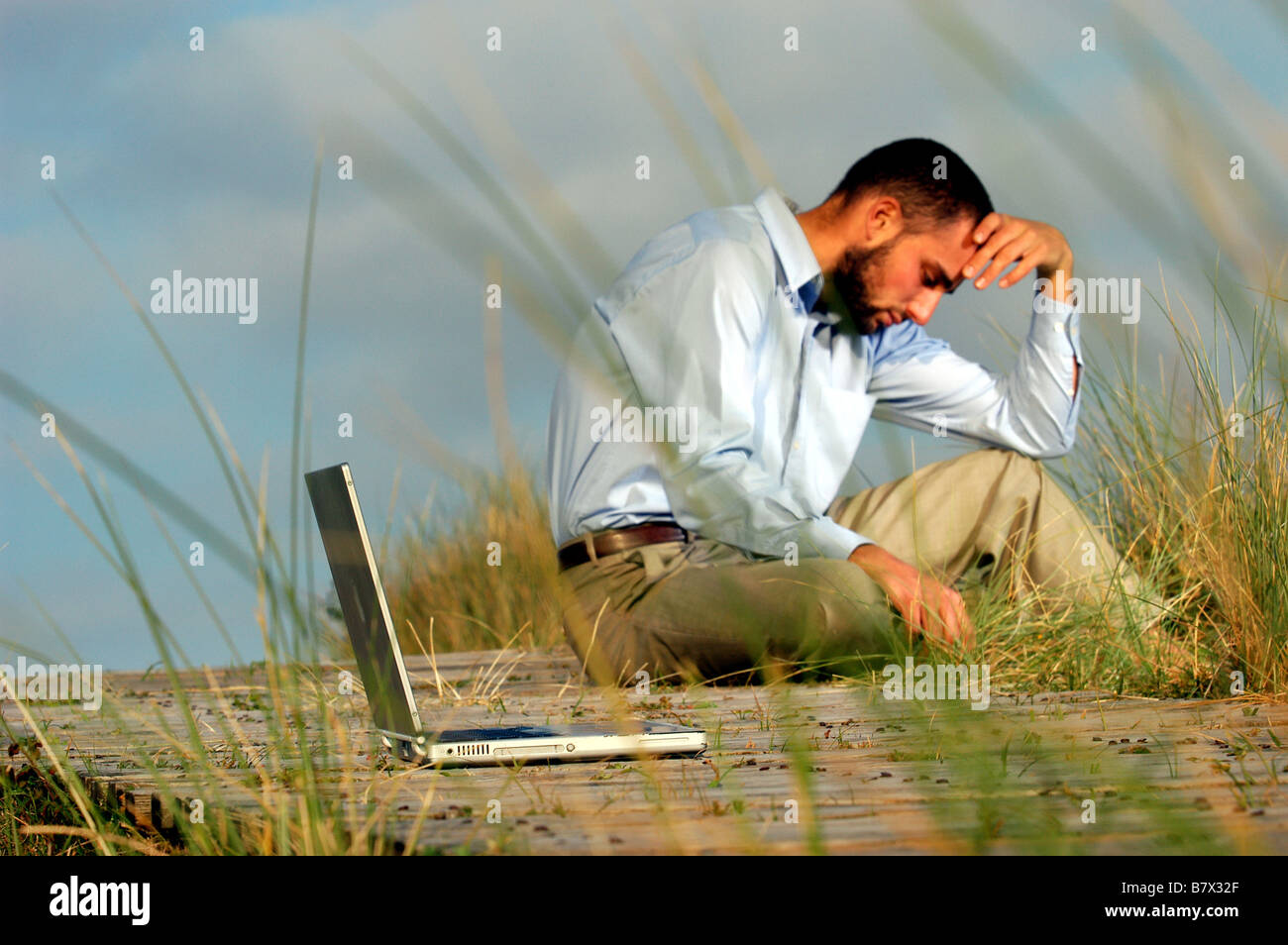 A depressed businessman at work outside with laptop computer and cell ...