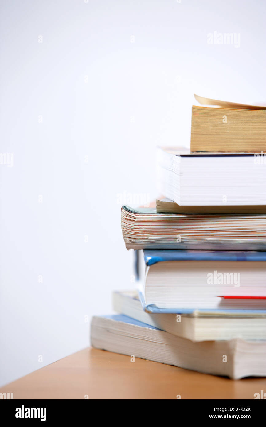 A stack of books sitting on the corner of a desk Stock Photo - Alamy