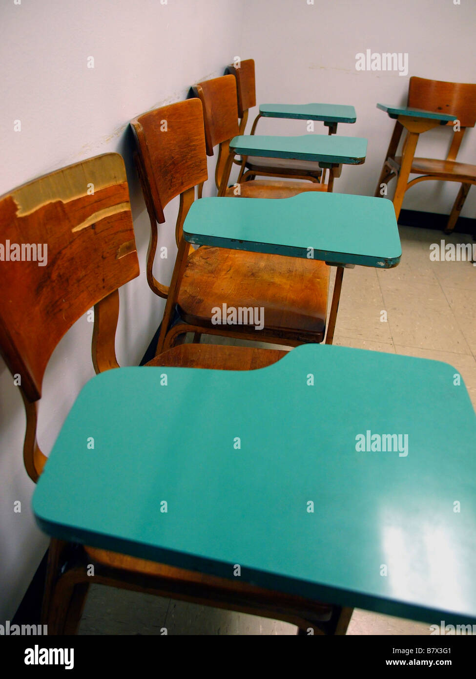 Rows of empty wooden antique desk-chairs with turqouise writing ...