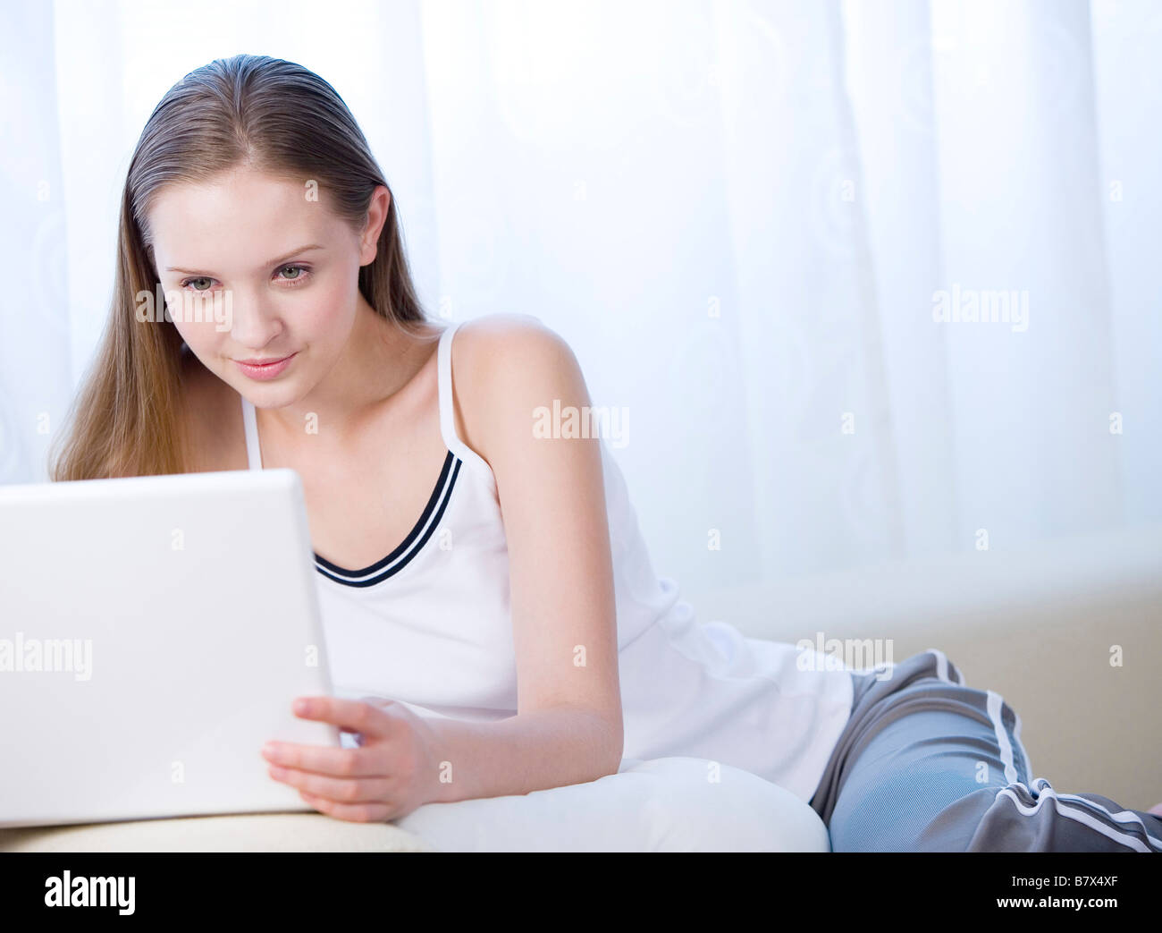Young woman sitting on sofa using laptop Stock Photo - Alamy
