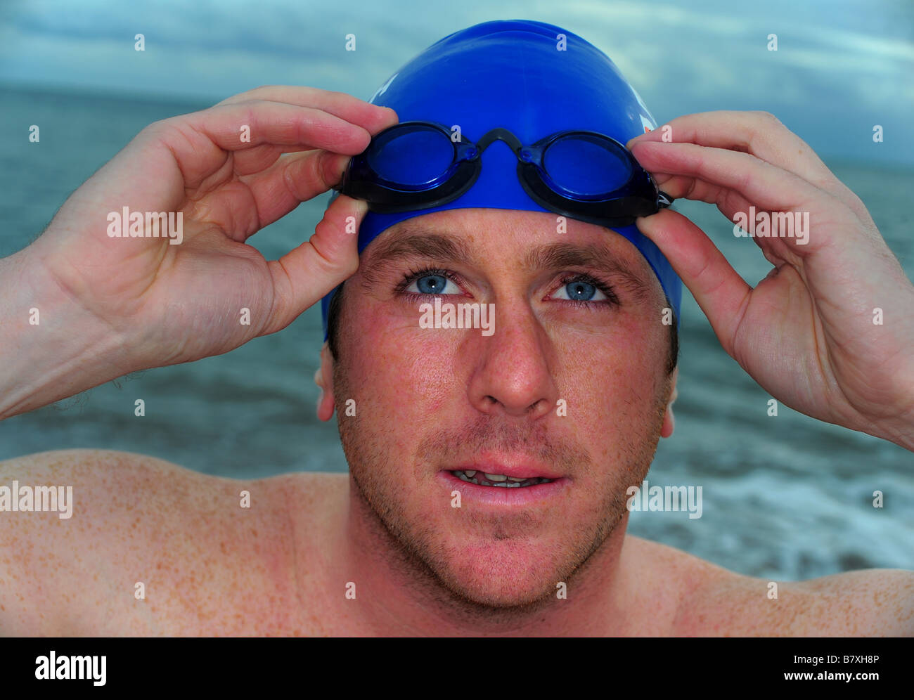 A man prepares to go sea swimming wearing a swimming cap and goggles on ...