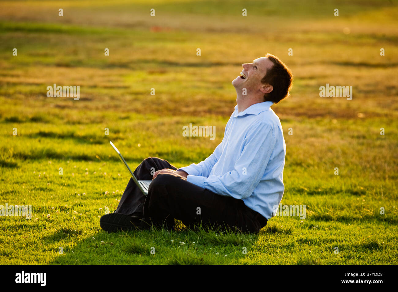 A man distance working on his laptop computer by a scenic harbor view ...