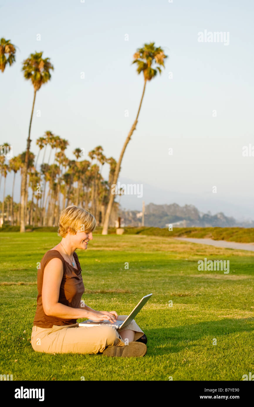 A woman works remotely on a computer outside in the park Stock Photo ...