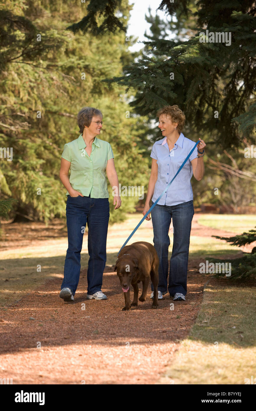 Two women walking a dog Stock Photo - Alamy