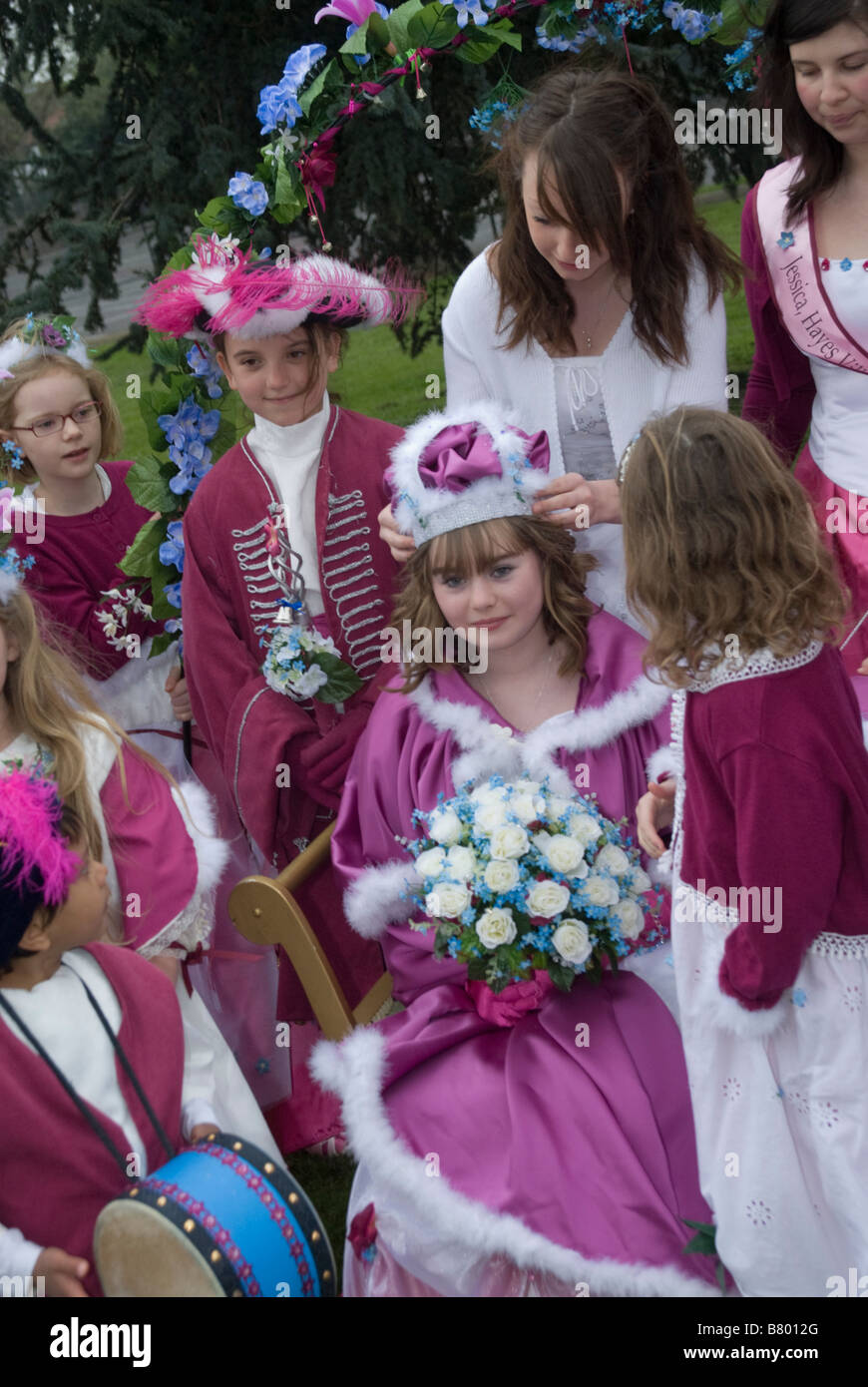 A May Queen is crowned by a previous May Queen at a crowning ceremony ...