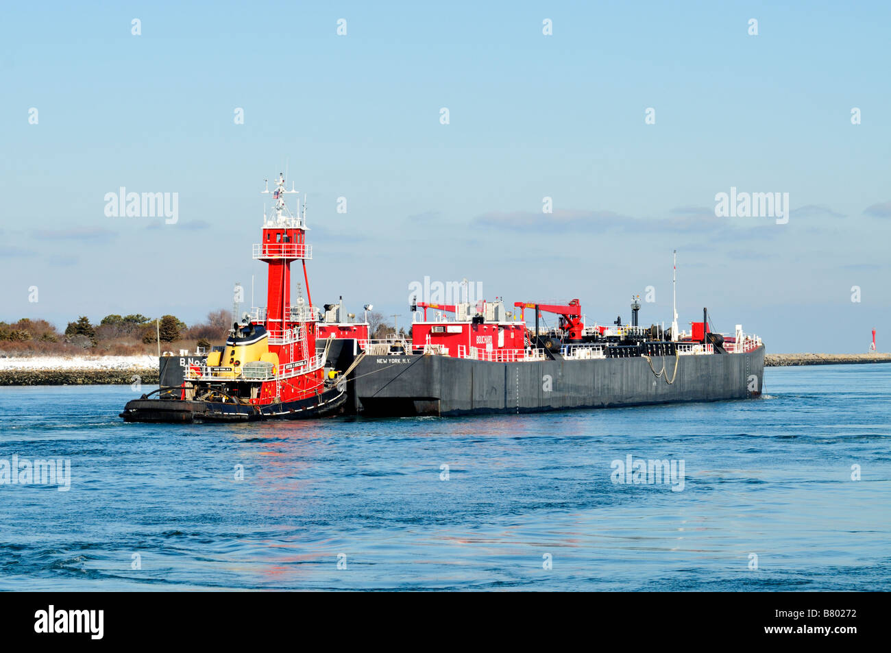 Red tugboat and barge heading out to sea on clear winter day from ...