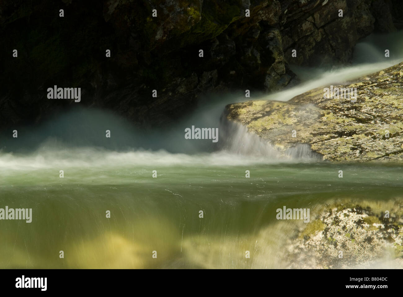 Water rolling down from and in between rocks and boulders in a river of ...