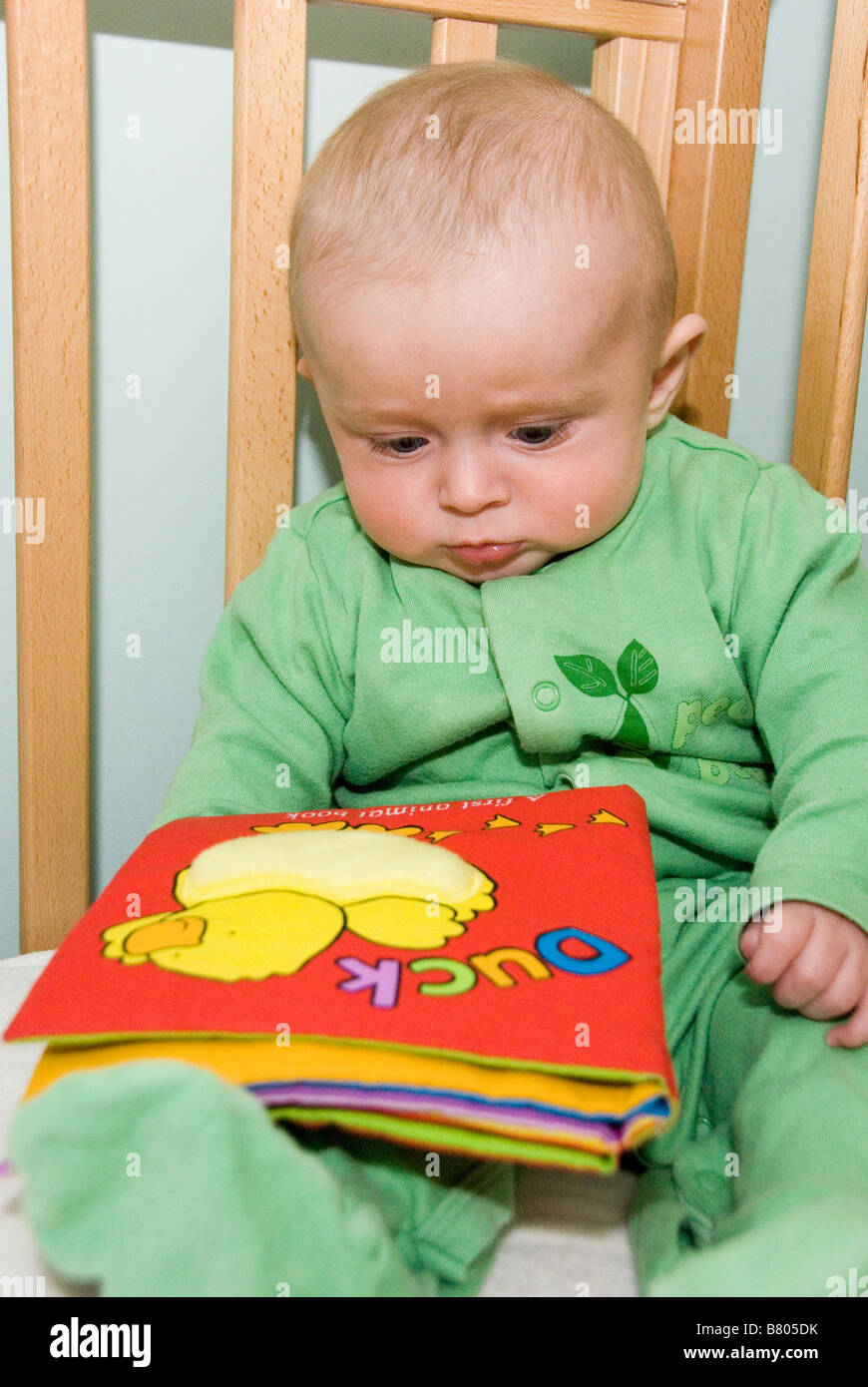 Baby Boy Sitting in Cot Playing with Material Book Stock Photo - Alamy