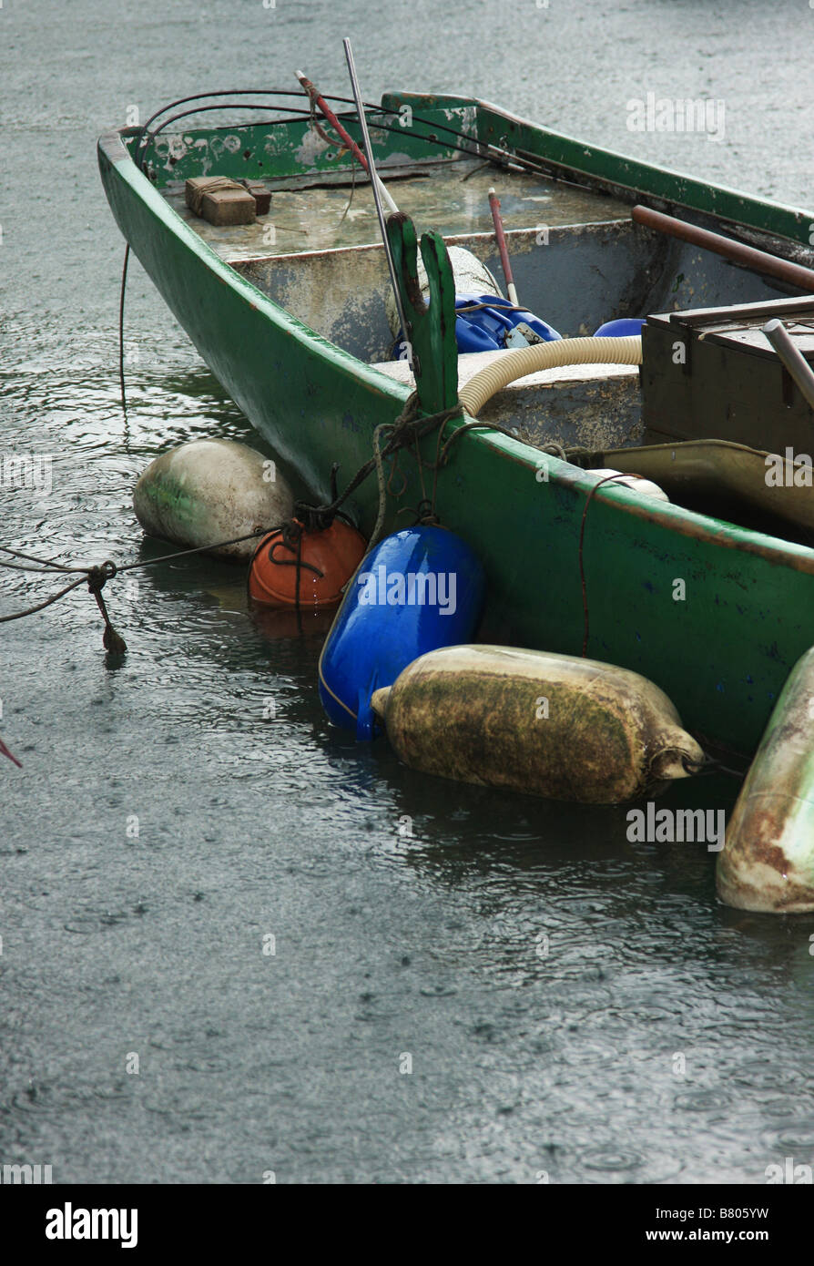 A dirty fishing boat floating on water in heavy rain Stock Photo - Alamy