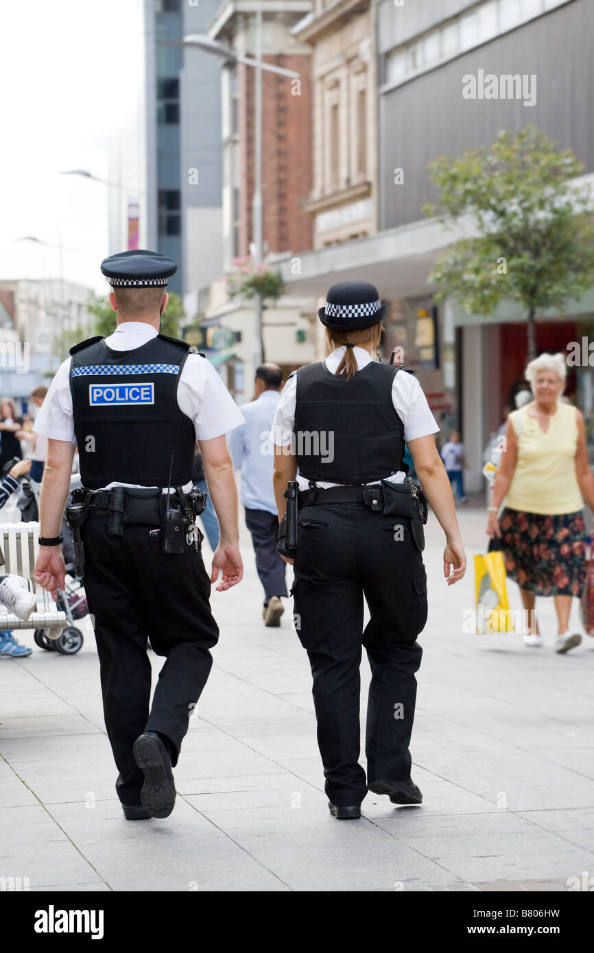 BACK VIEW OF TWO POLICE OFFICERS, MALE AND FEMALE, WALKING DOWN THE ...