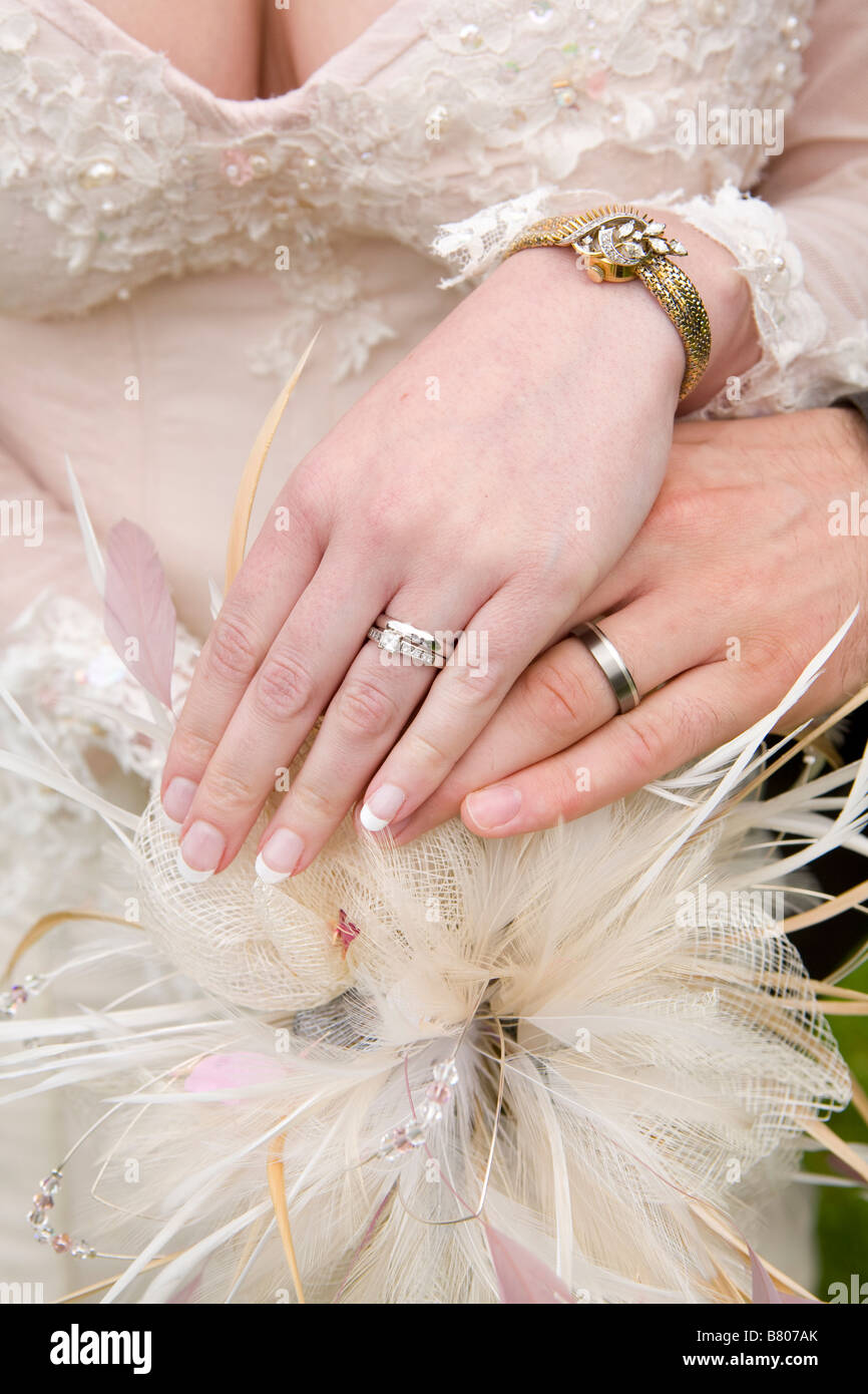 bride and grooms wedding ring on hands over vintage themed bouquet ...