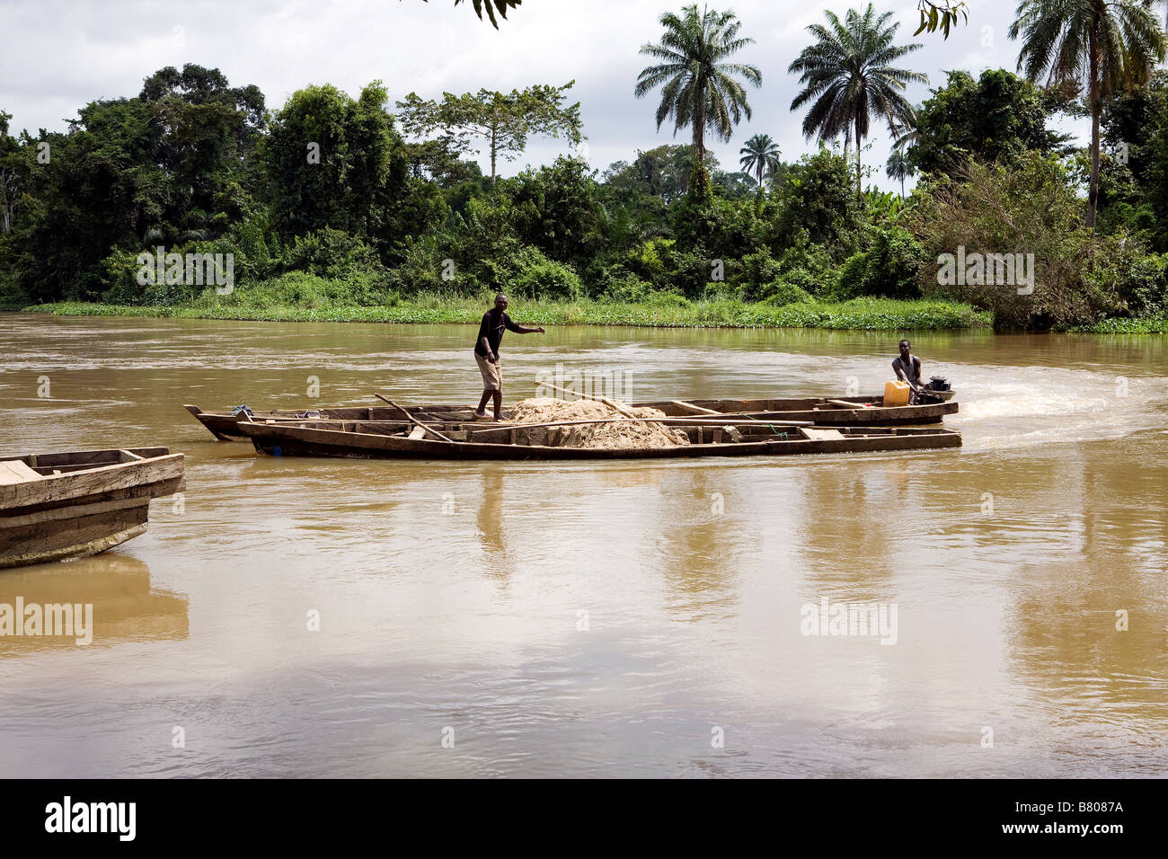 Two flat-bottomed boats that have been tied together and manned by two ...