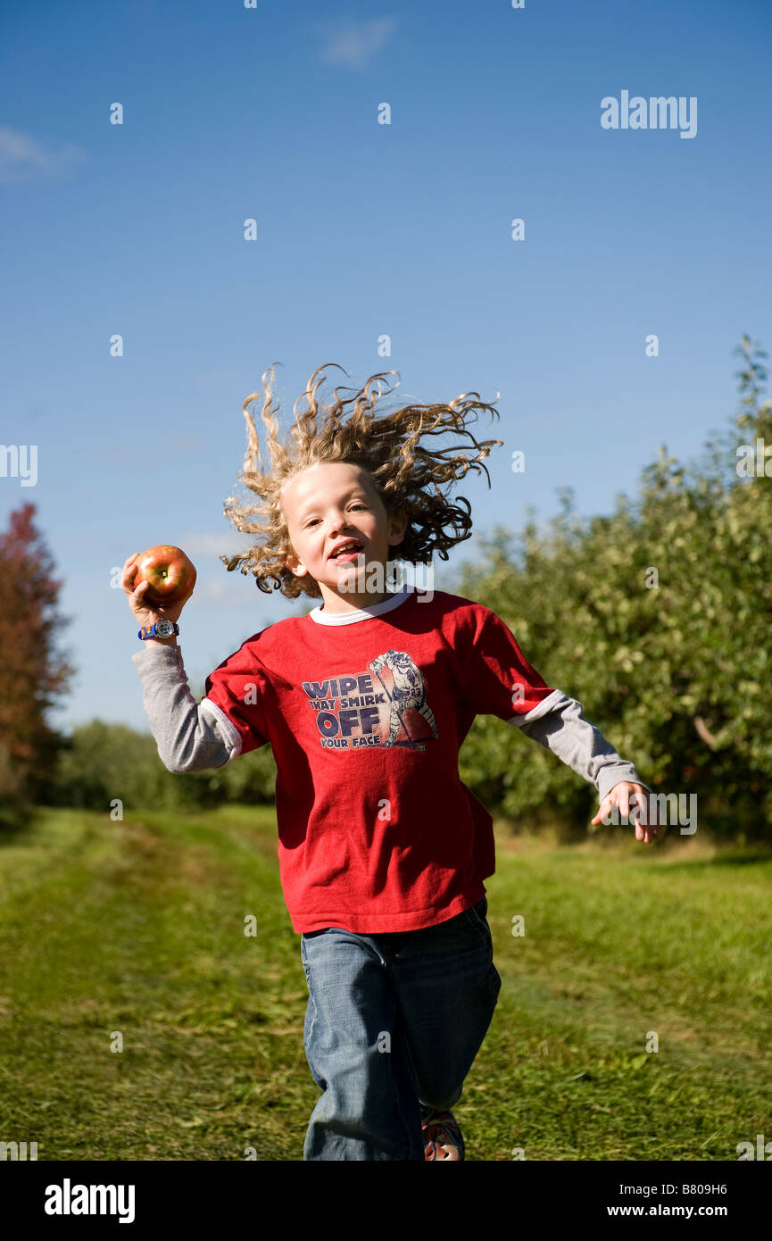 A young boy running through an apple orchard with his dog Stock Photo ...