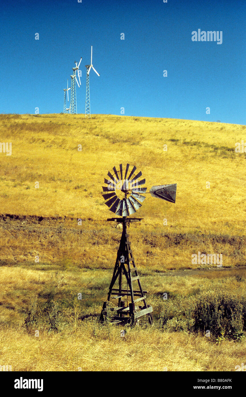 Old fashioned water windmill rests below modern wind-powered electric ...