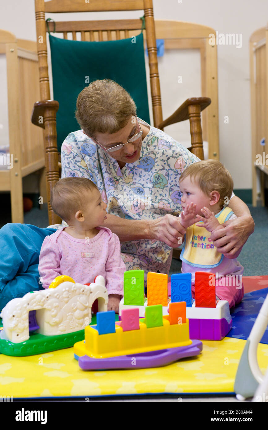 Senior preschool daycare worker using bright colored toys to teach ...