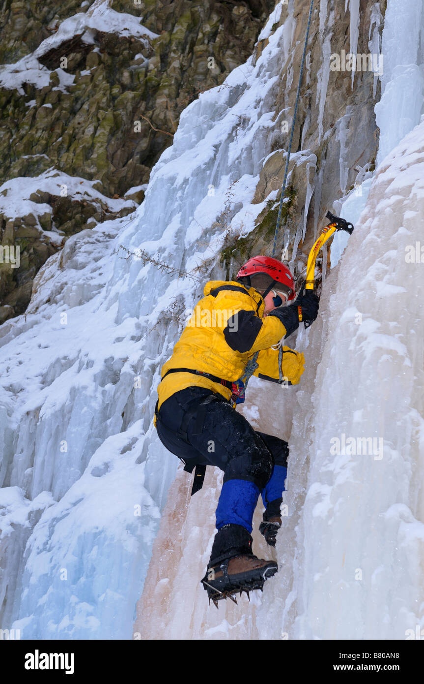 Ice climber struggling up a steep icefall in cliff at Tiffany Falls ...