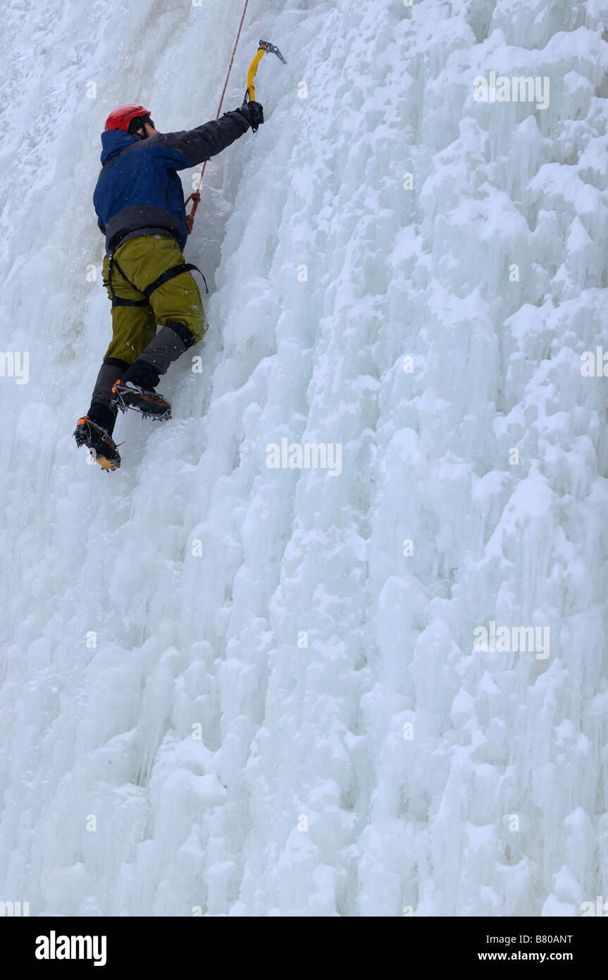 Single ice climber front pointing up a wall of ice on belay at Tiffany ...