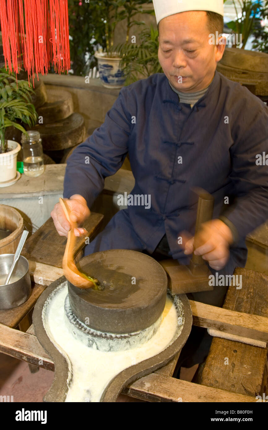 A chef making tofu with a traditional stone mill in a restaurant in ...