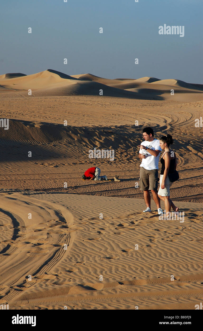 Praying in the desert, man at prayer, 2 tourists, Margham Desert, near ...