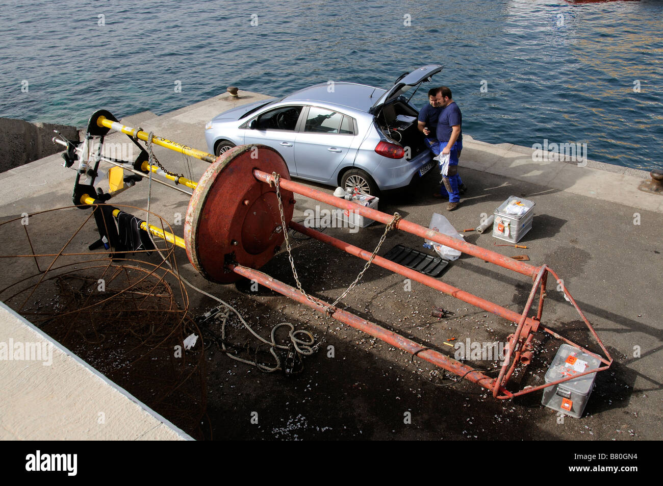 Service engineers working on ocean navigational buoy on the harbour at ...
