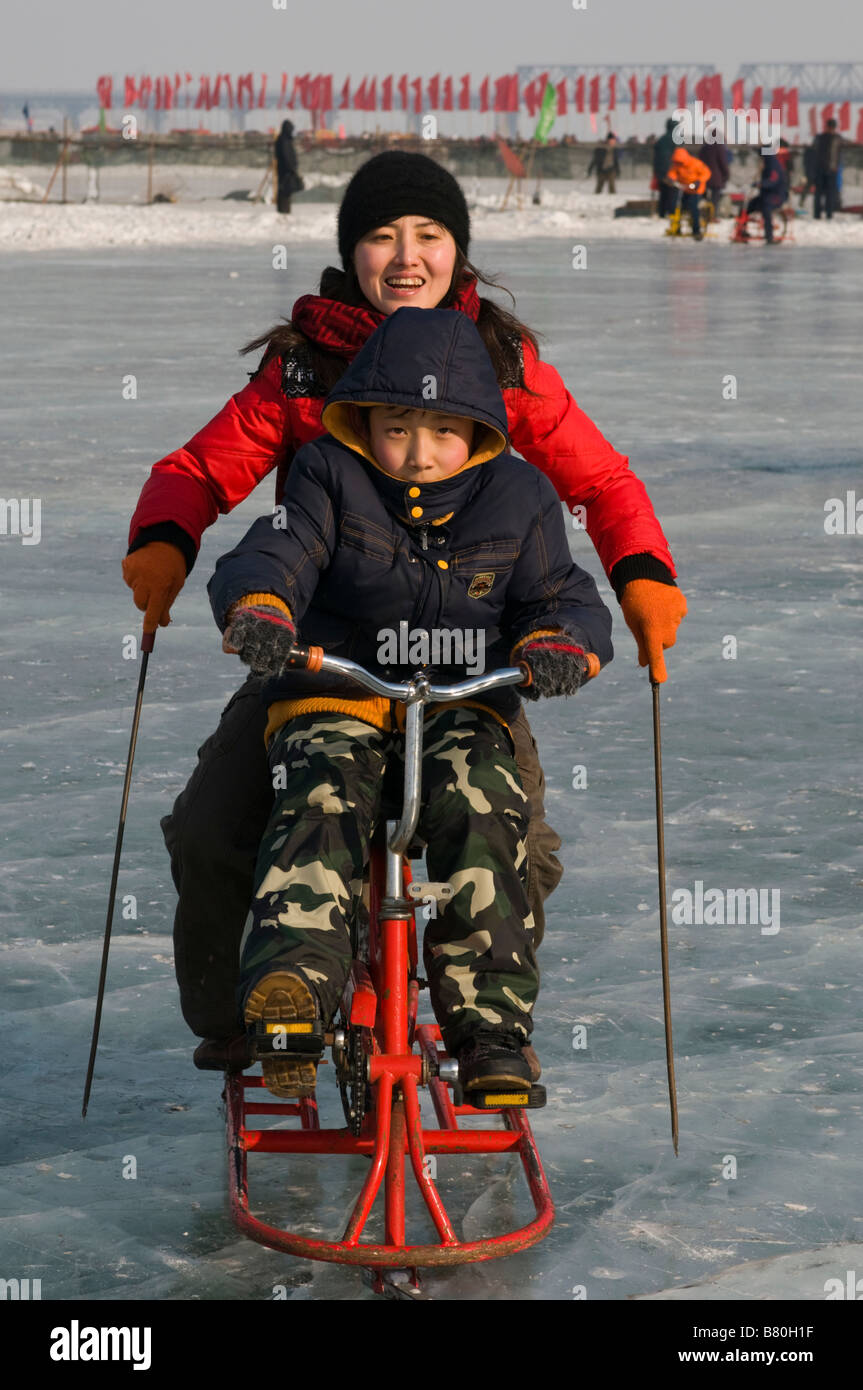 A mother and son riding a sled on the frozen Songhua River, Harbin ...