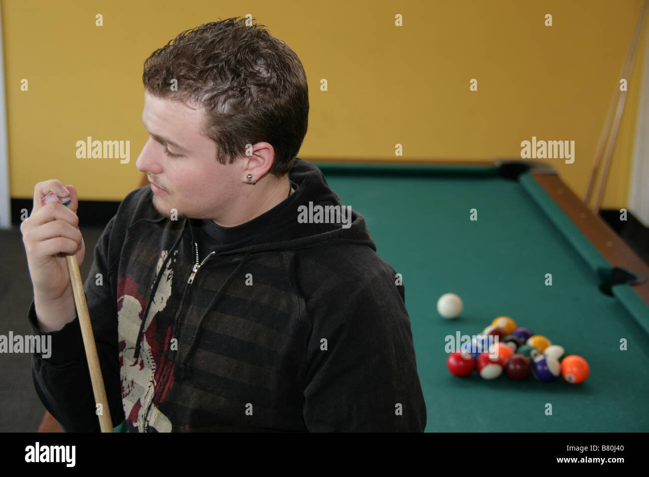 Young man chalking his pool stick Stock Photo - Alamy