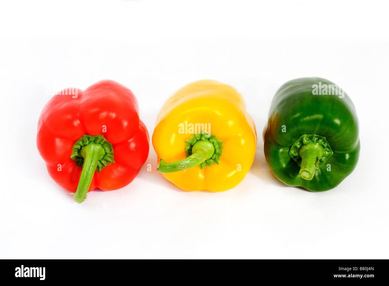 Three bell peppers in a row on a white background Stock Photo - Alamy