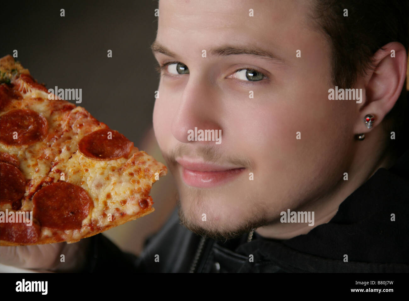 Young man eating a slice of pizza Stock Photo - Alamy