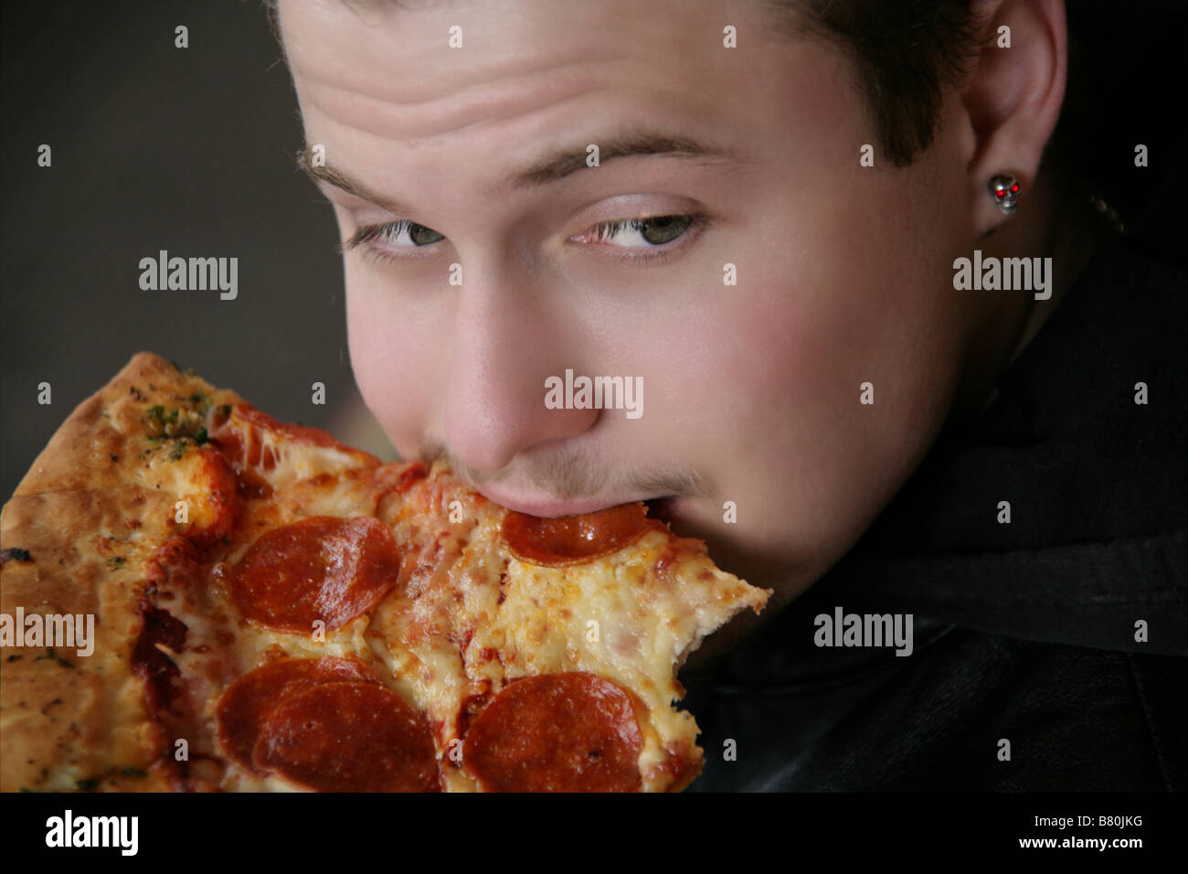 Young man eating a slice of pizza Stock Photo - Alamy