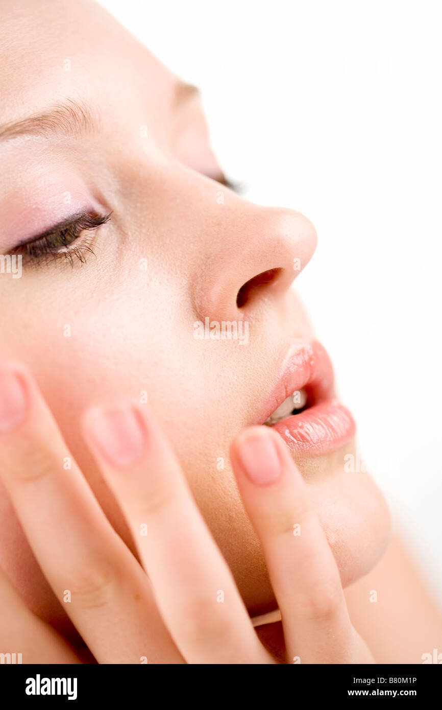 Close up to a young woman s face with fingers on her right cheek side ...