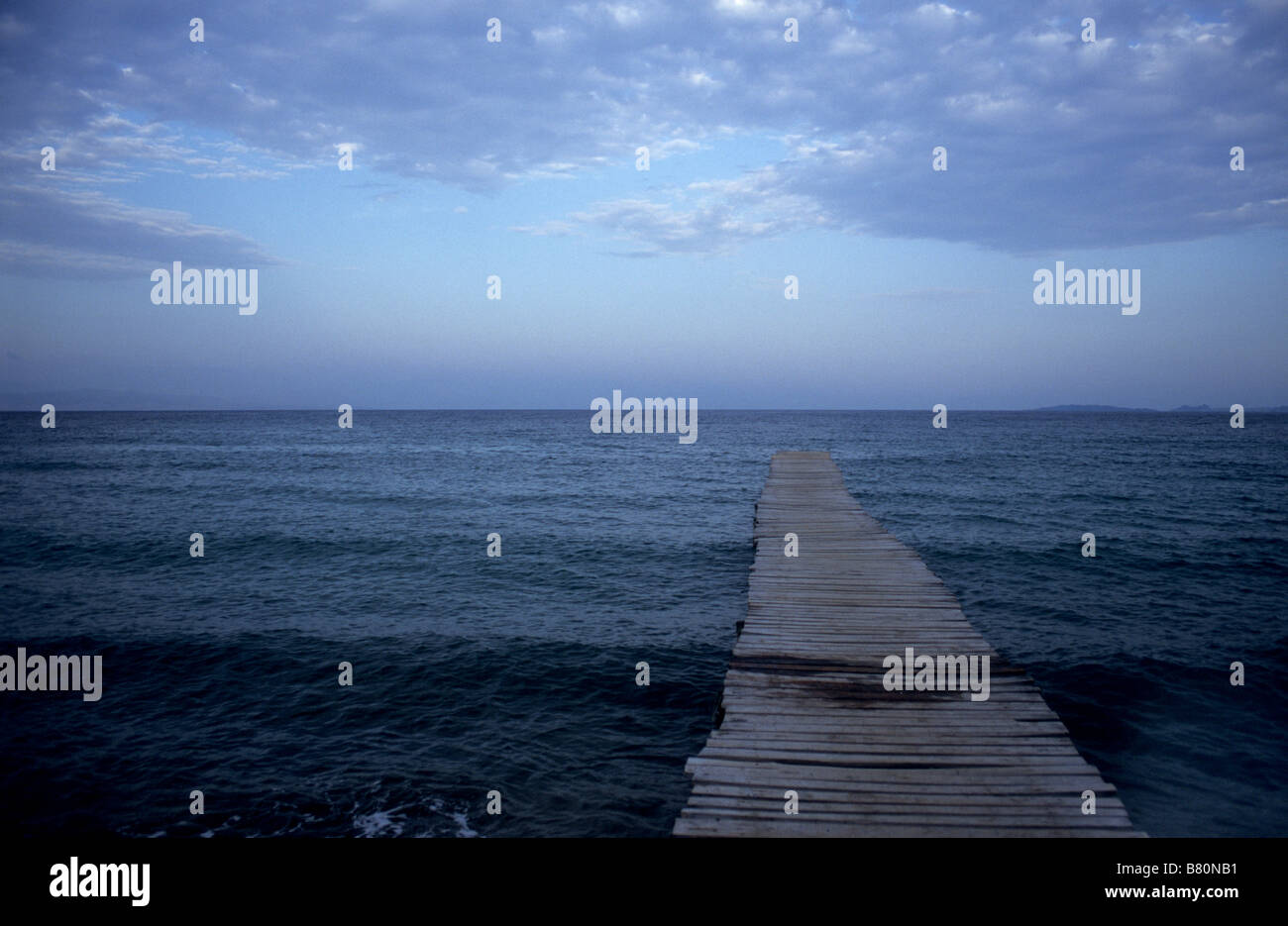 Wooden pier extending into the deep blue sea Stock Photo - Alamy