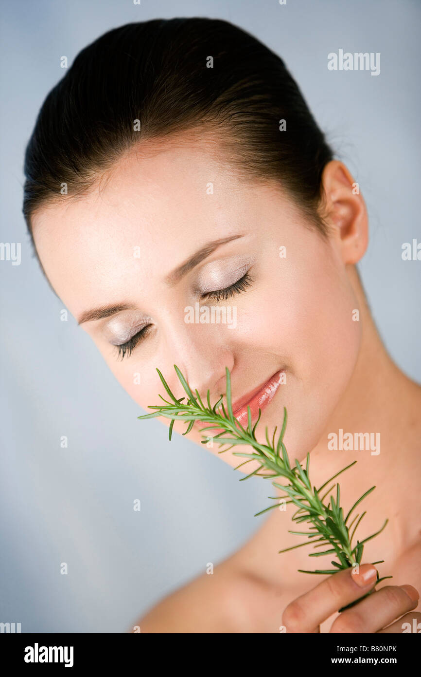 Young woman holding sprig of rosemary head and shoulder smiling eyes ...