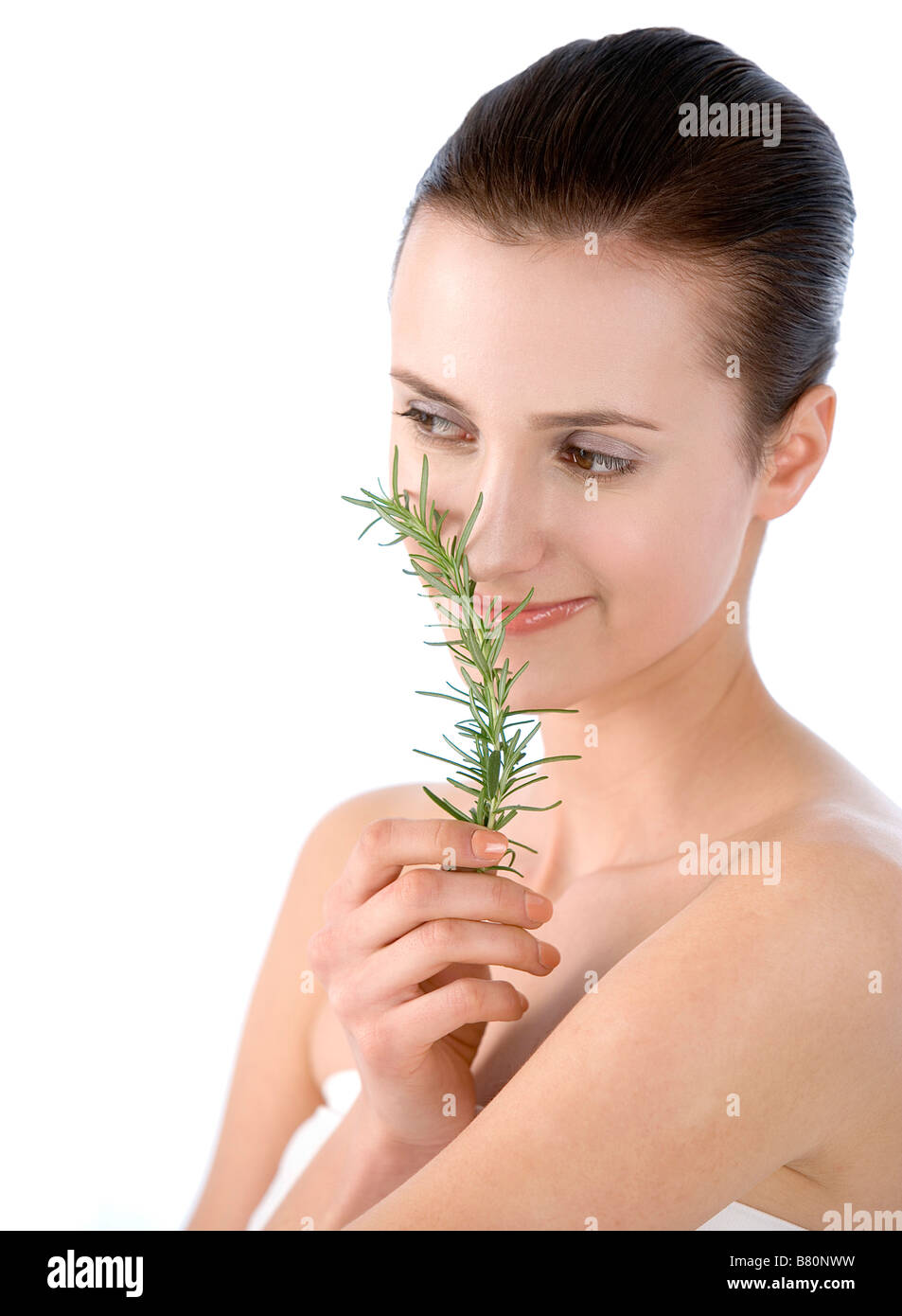 Young woman holding sprig of rosemary smiling head and shoulder side ...