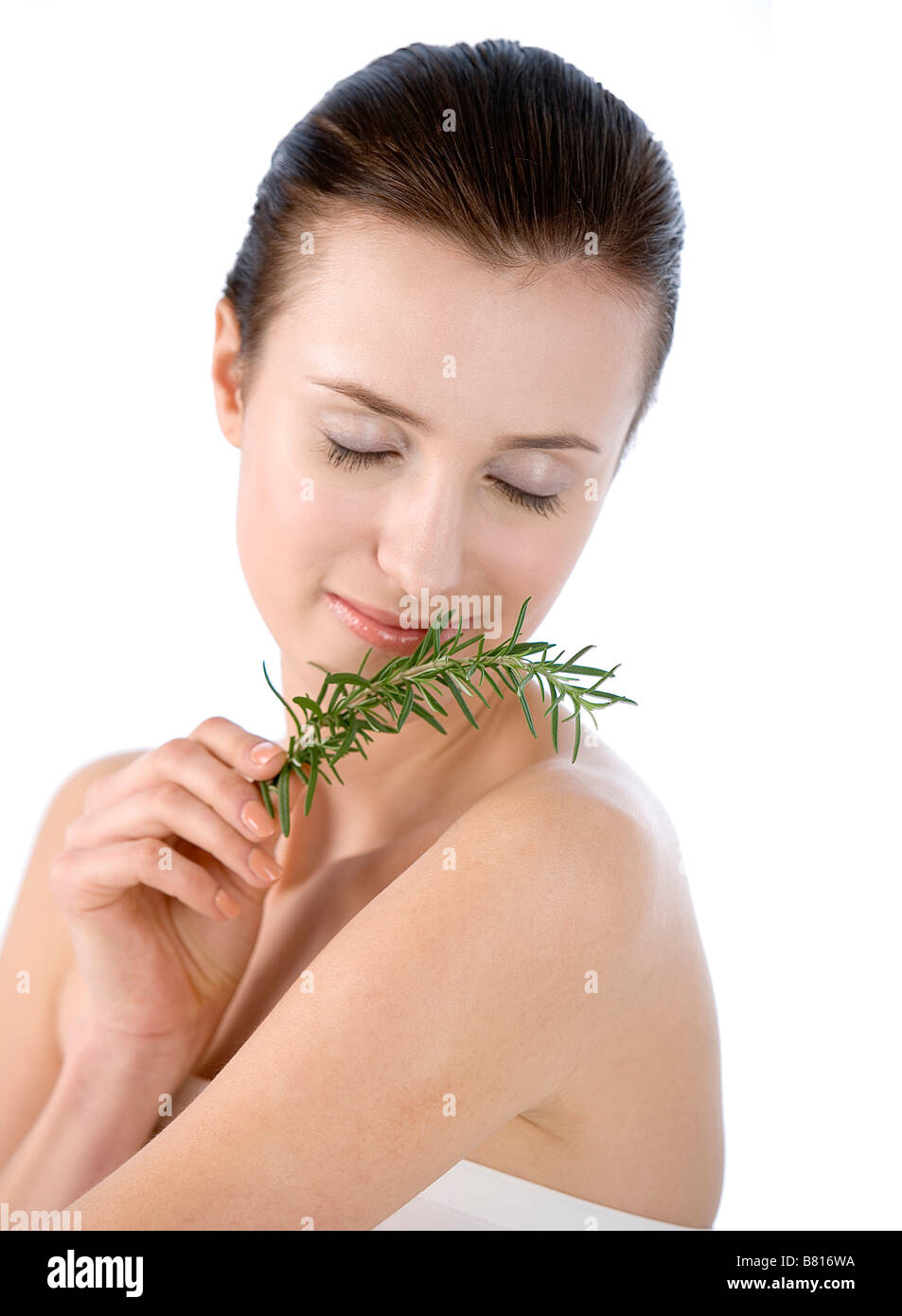 Young woman holding sprig of rosemary smiling head and shoulder side ...