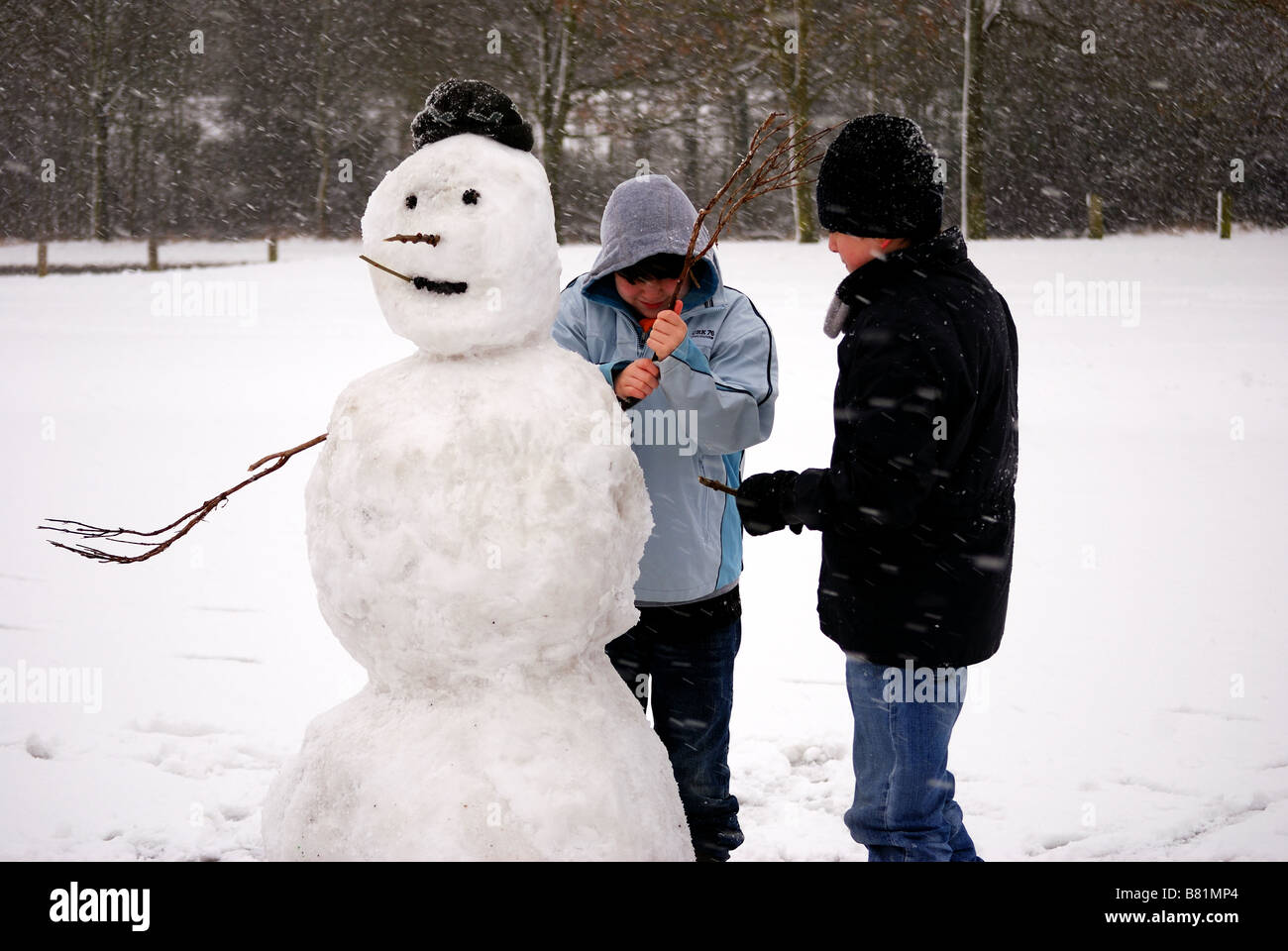 Boys building a snowman Stock Photo - Alamy