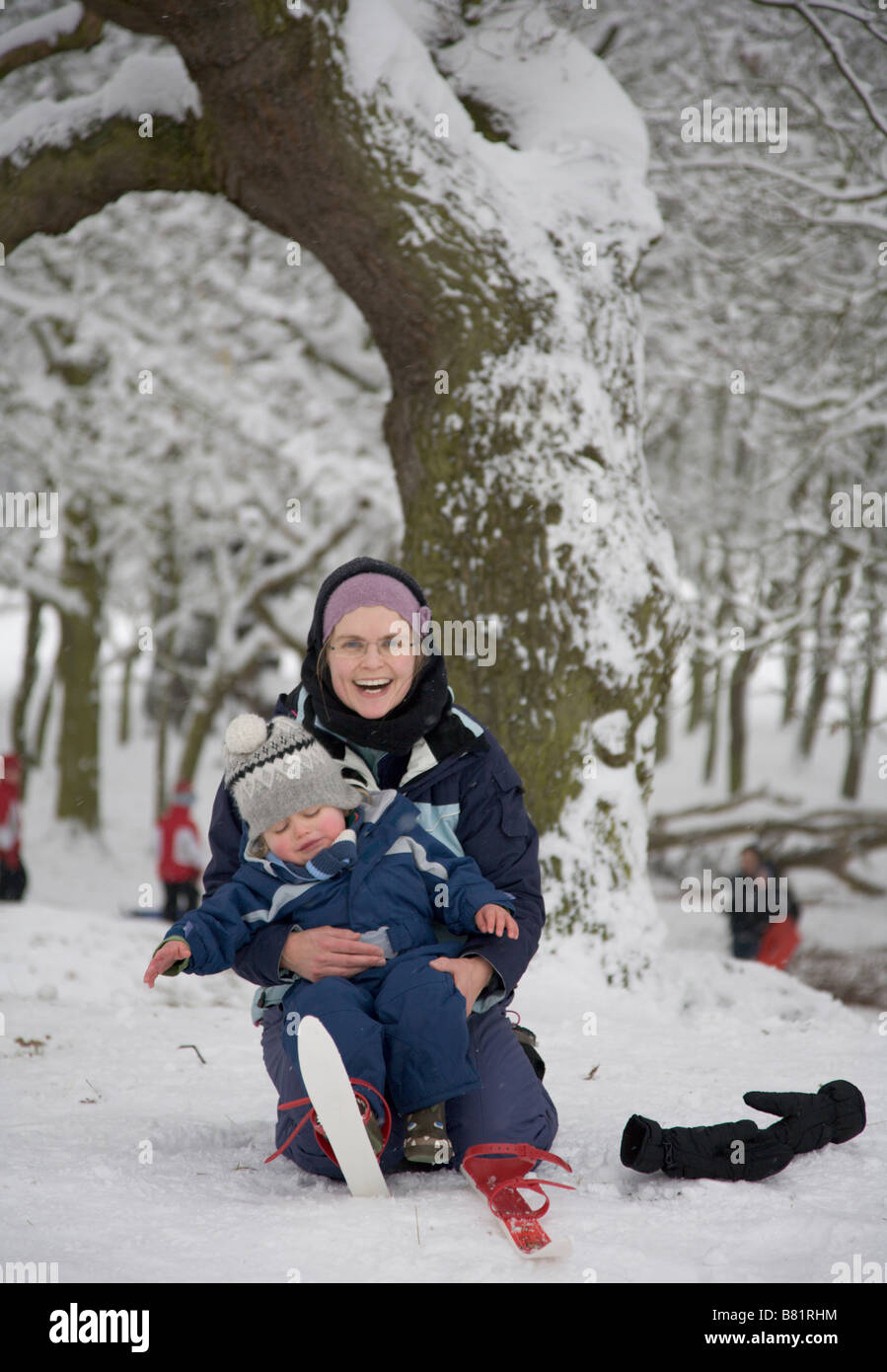 A mother teaches her young child to ski during the winter snowfall in ...