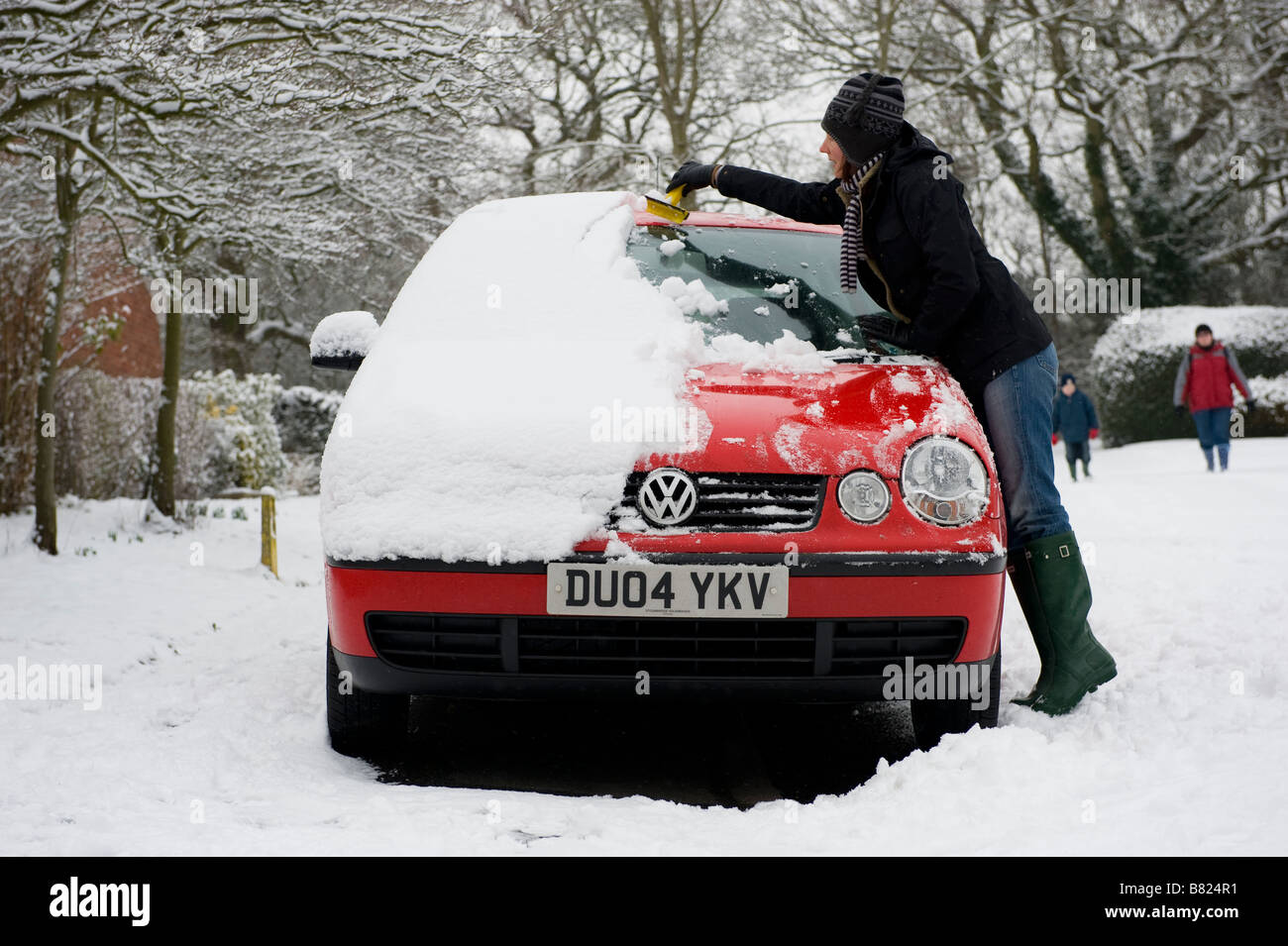 A woman clears heavy snow from her car before attempting to drive to work. Heavy snowfall brings ...