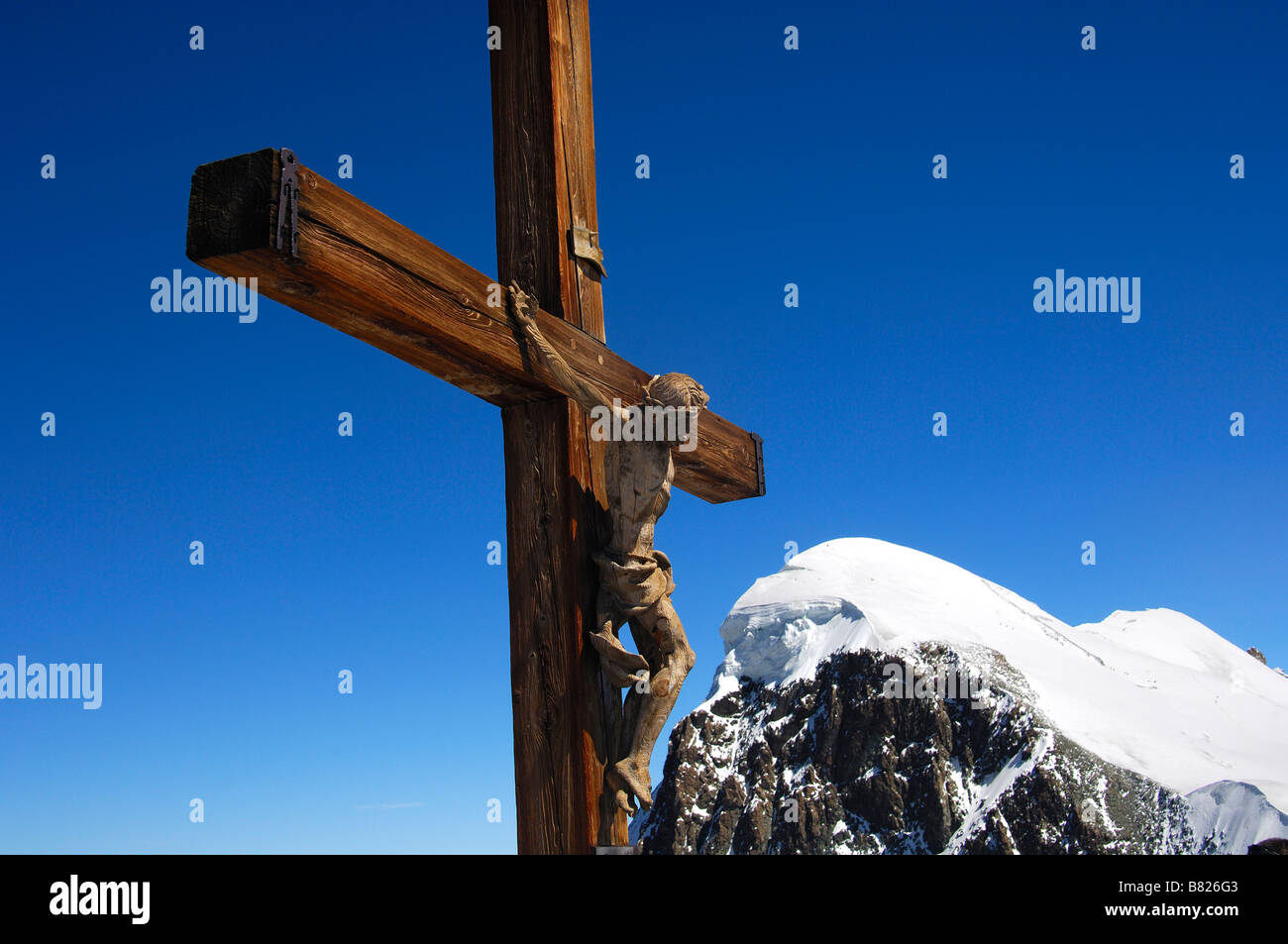 A Christ sculpture nailed onto a wooden cross against the snow covered ...