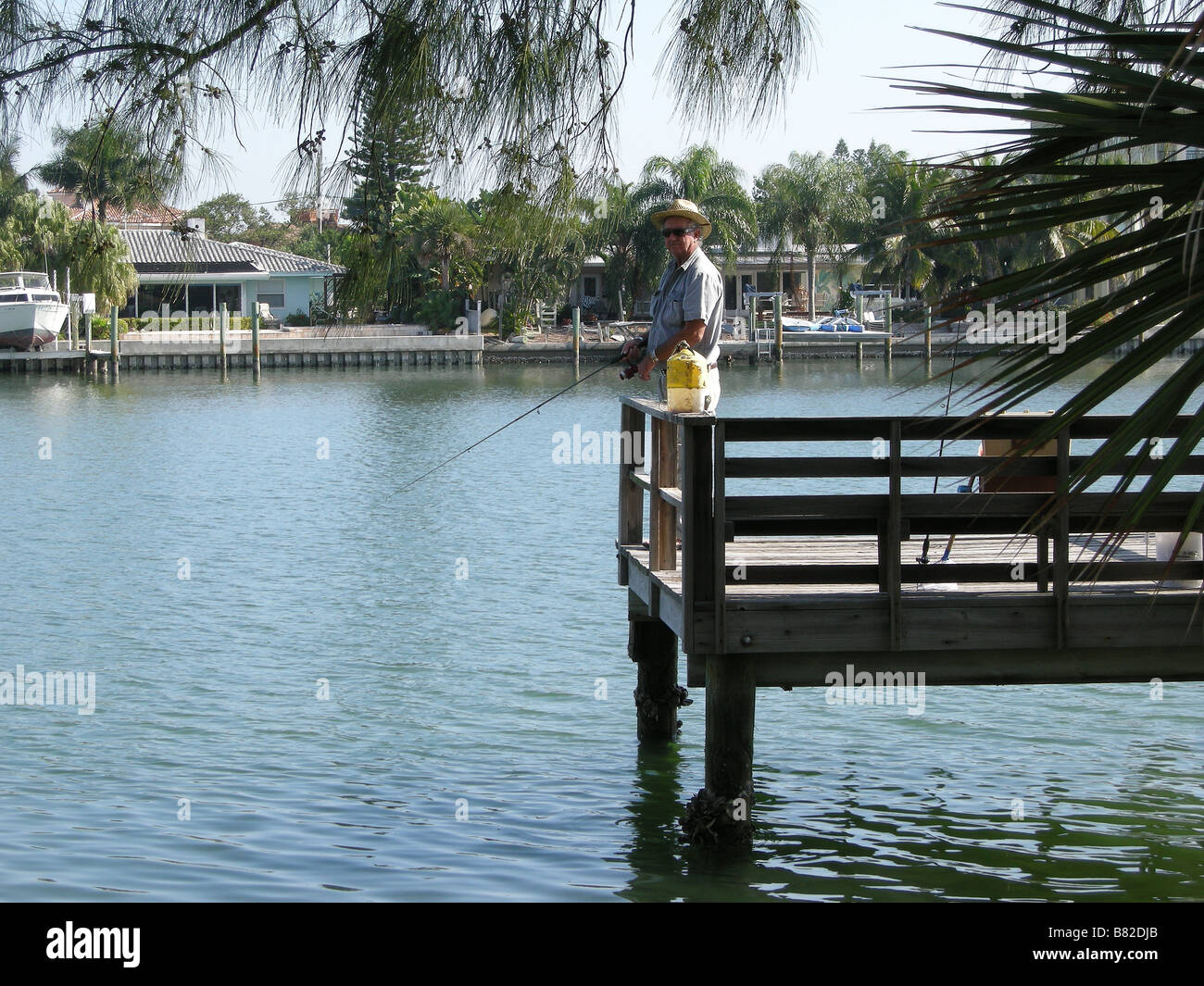A man fishing off a pier in blue Florida waters Stock Photo - Alamy