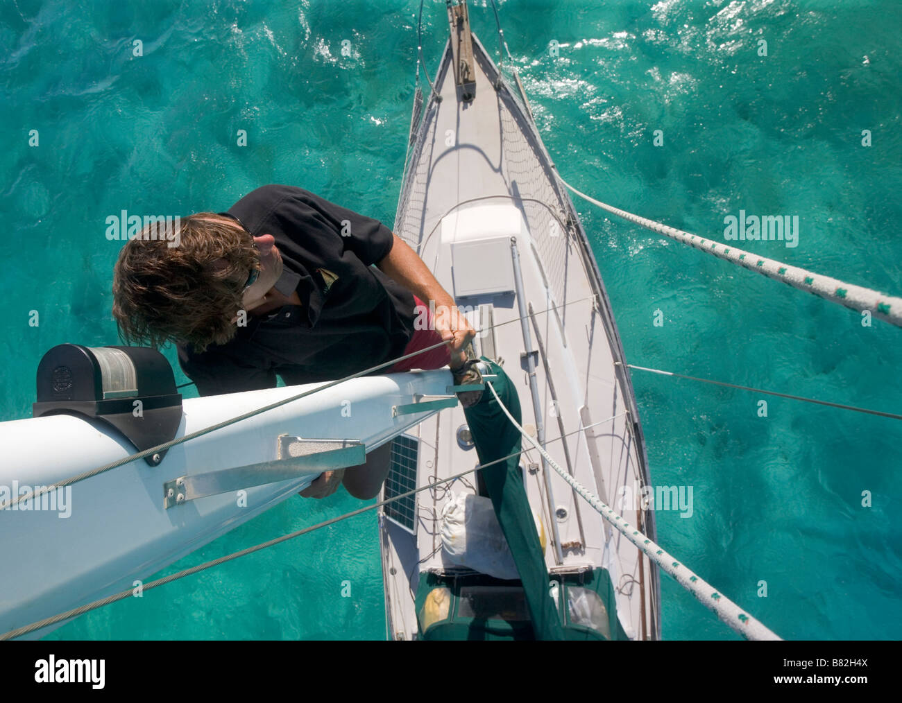 A sailor looks out from halfway up the mast on a cruising sailboat in ...