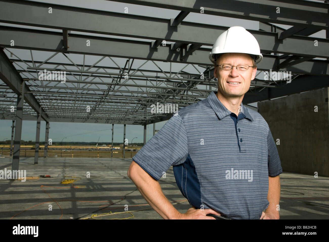 Man with a hard hat standing by building under construction Stock Photo ...